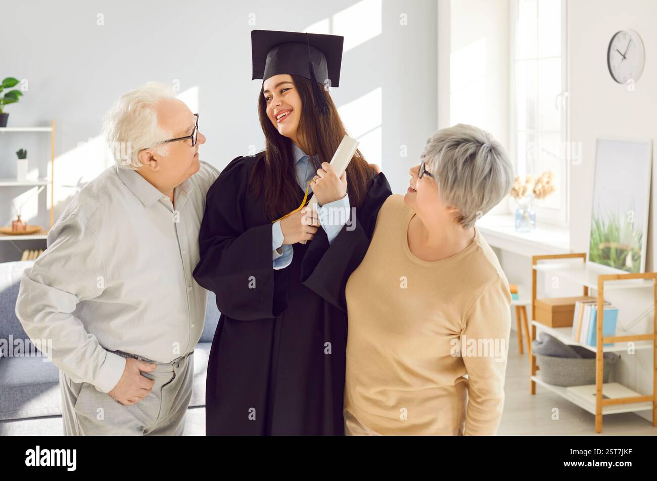 Graduate woman in cap and gown in hugs of parents graduation from ...