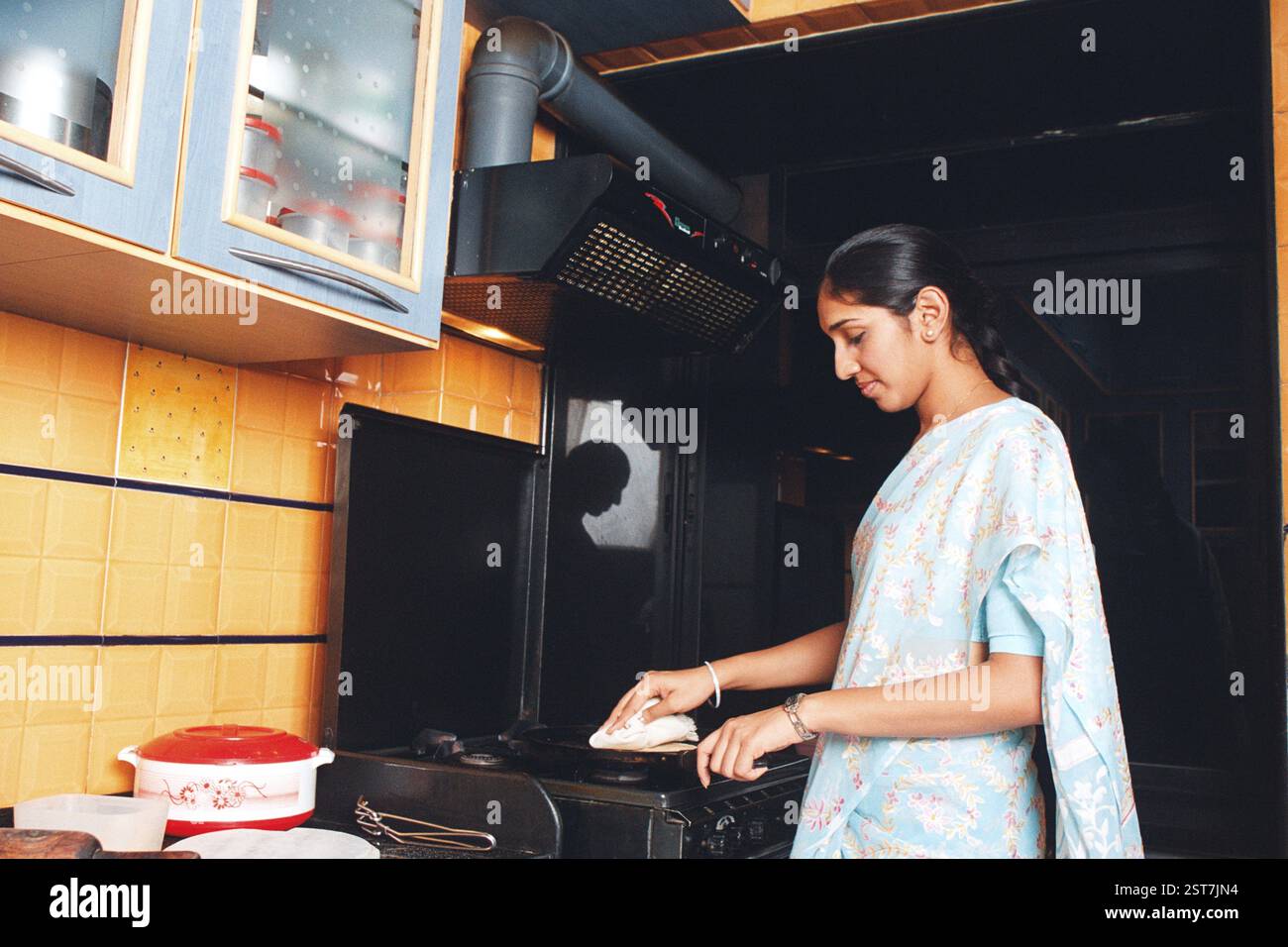 South Asian Indian Woman working in kitchen cleaning cooking range ...