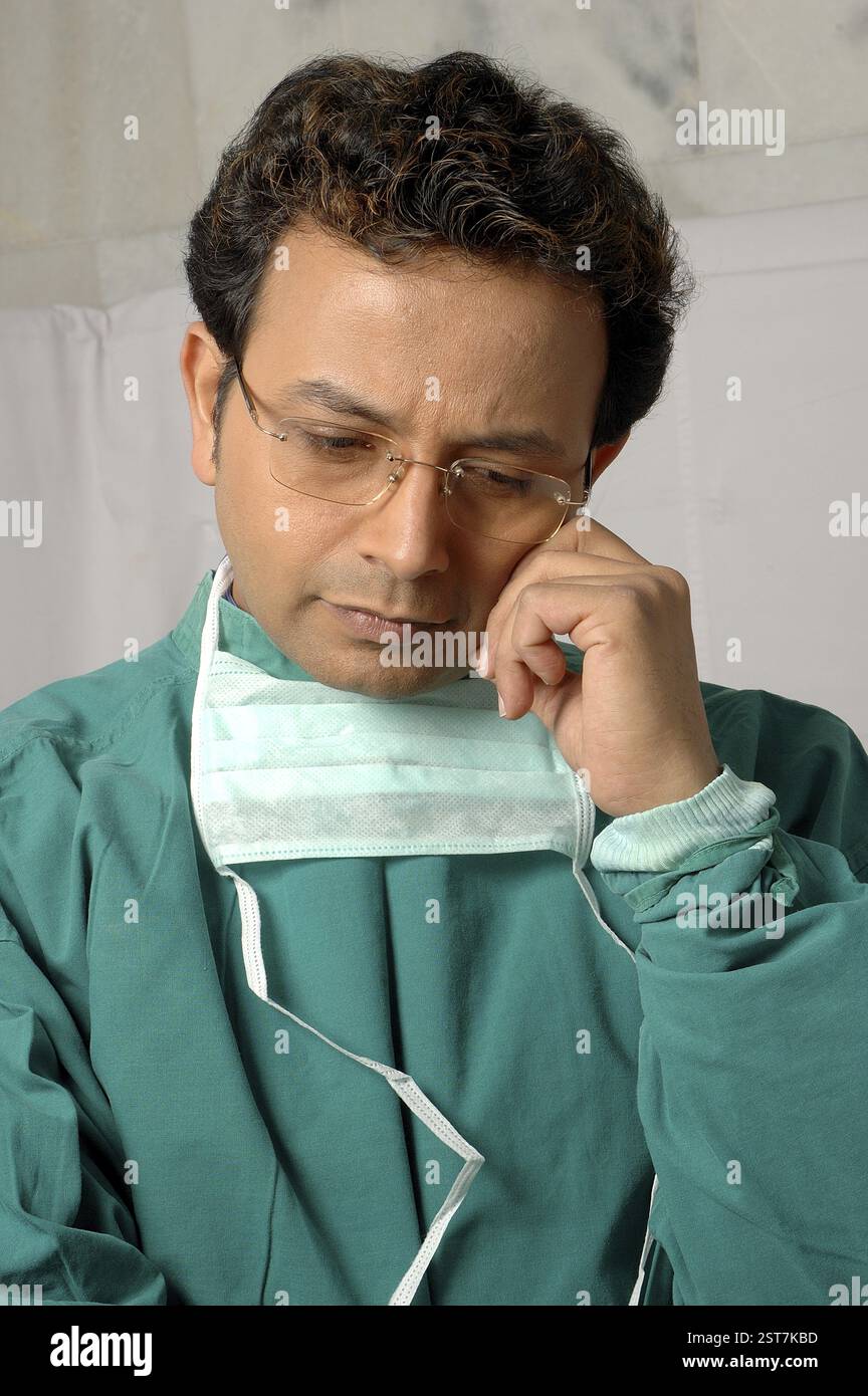 Young Indian Doctor surgeon, serious, in green operation theatre coat ...