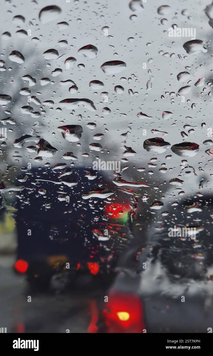 Melted snow and rain drops on the windshield of a car. Blurred outdoor ...