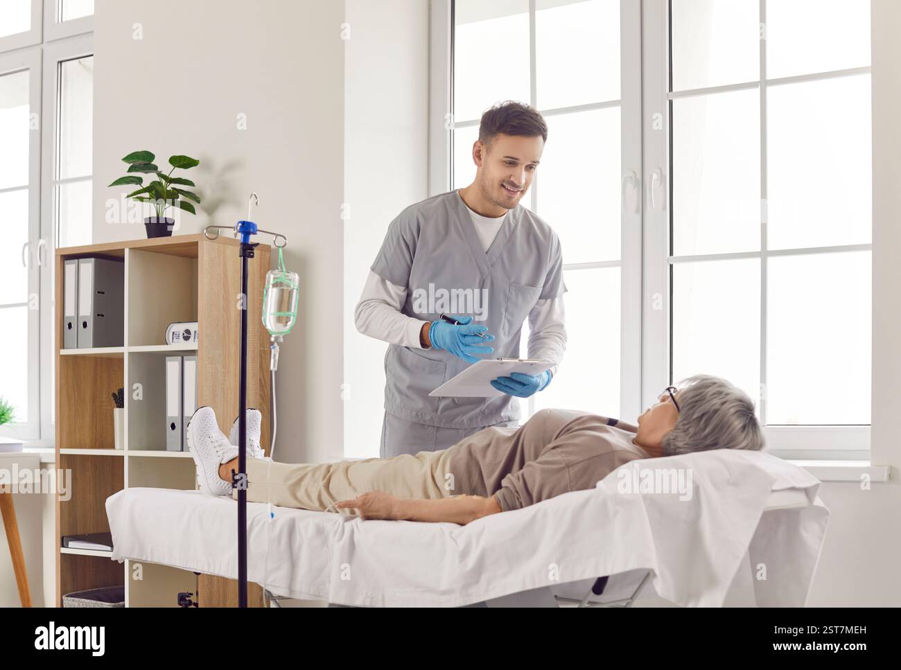 Woman senior patient lying on couch in clinic and receiving IV drip ...