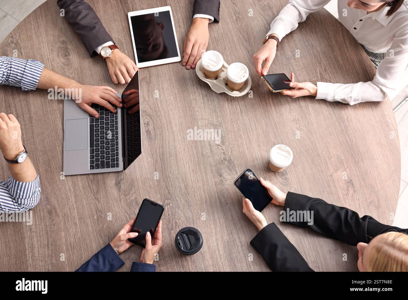 Group of people using different gadgets at wooden table in office, top ...