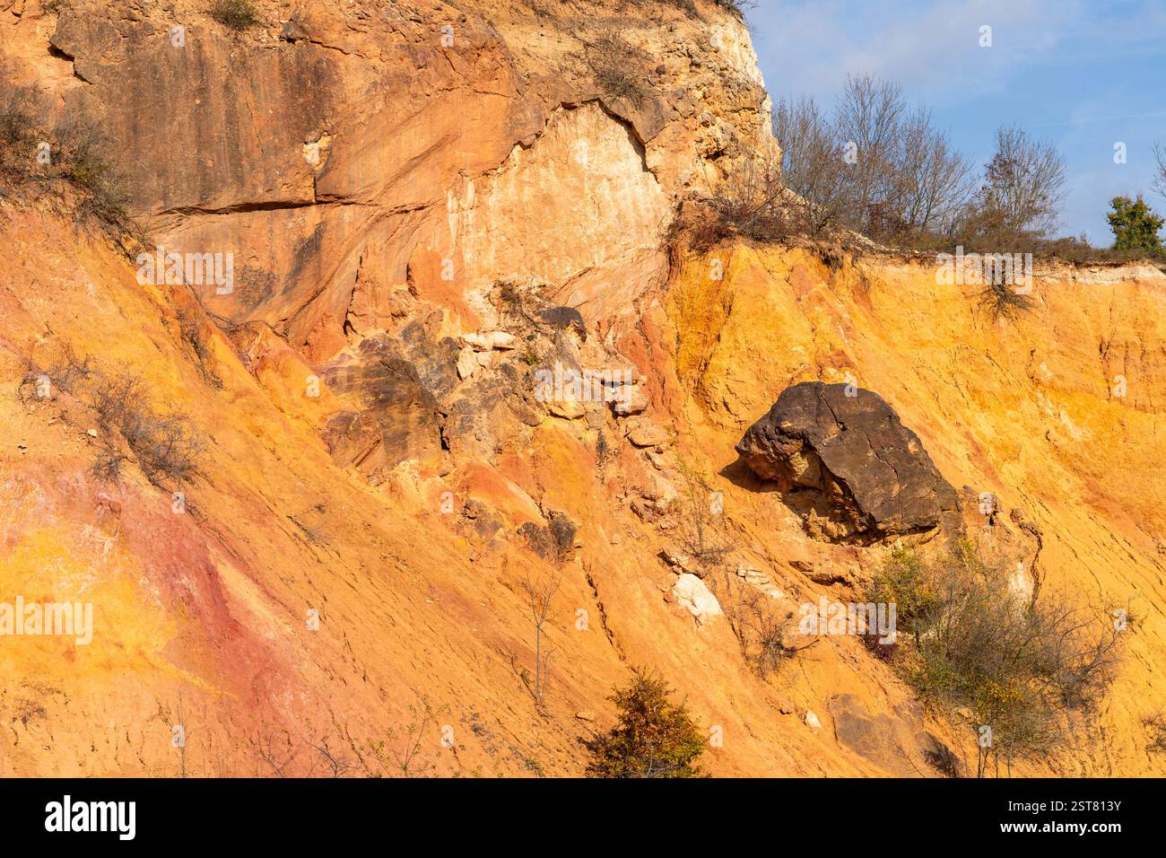 Eroded bauxite rock formation with bright orange colors in an abandoned ...