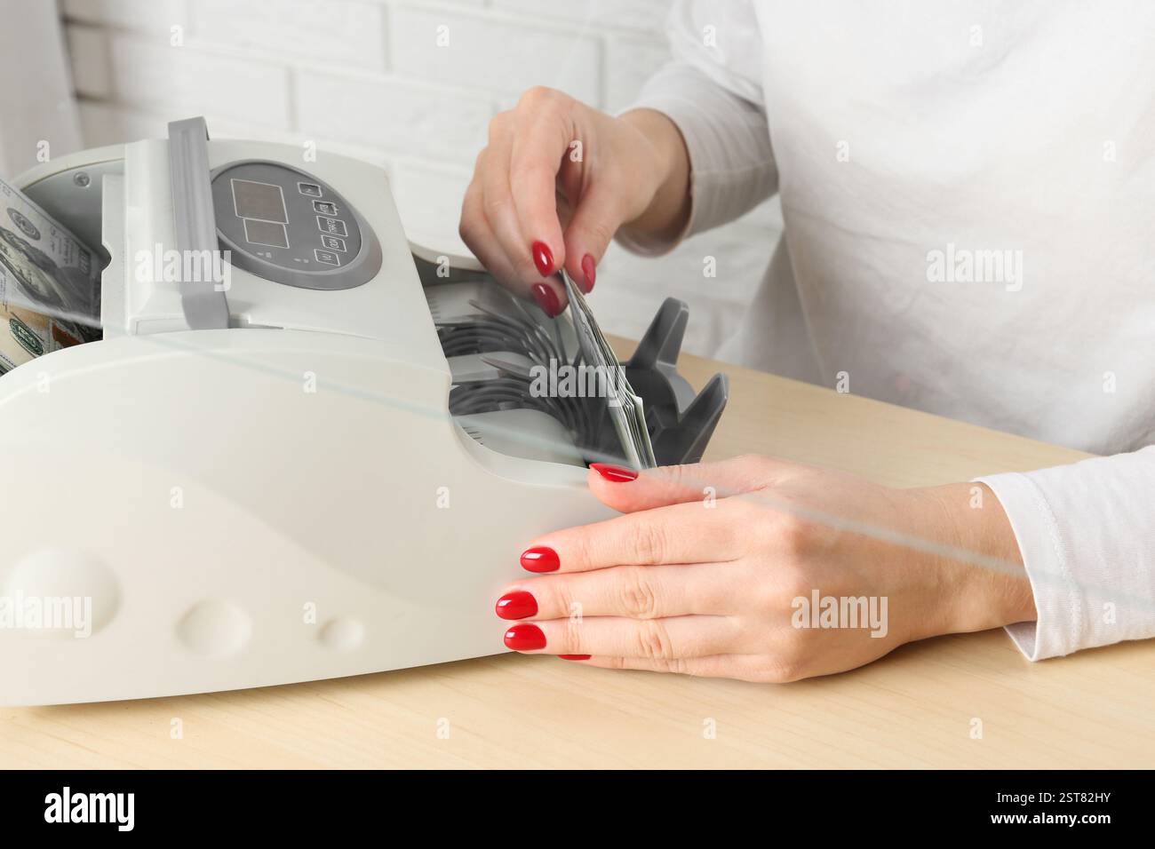Cashier using money counting machine at table in currency exchange ...