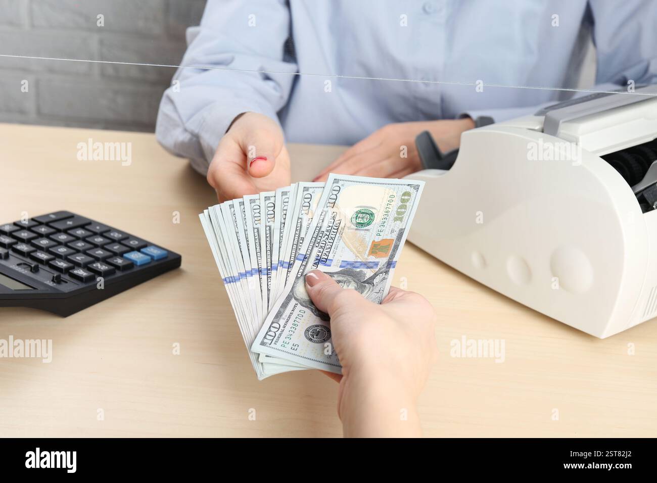 Client giving dollar banknotes to cashier at table in money exchange ...