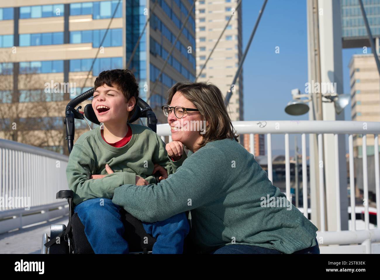 Happy boy with disability smiling with his mother on a bridge in the ...