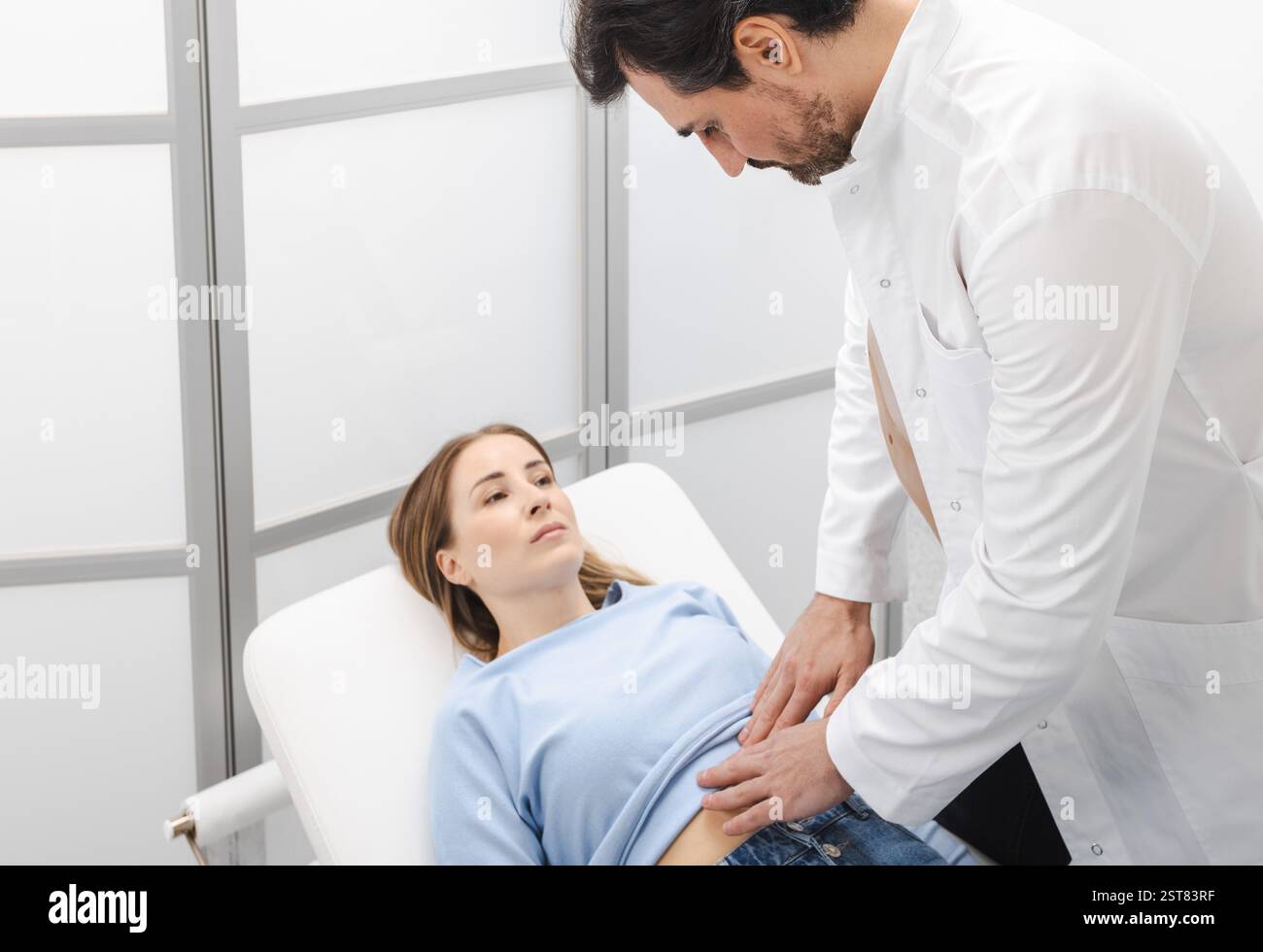 Doctor gastroenterologist palpating female patient's stomach and ...