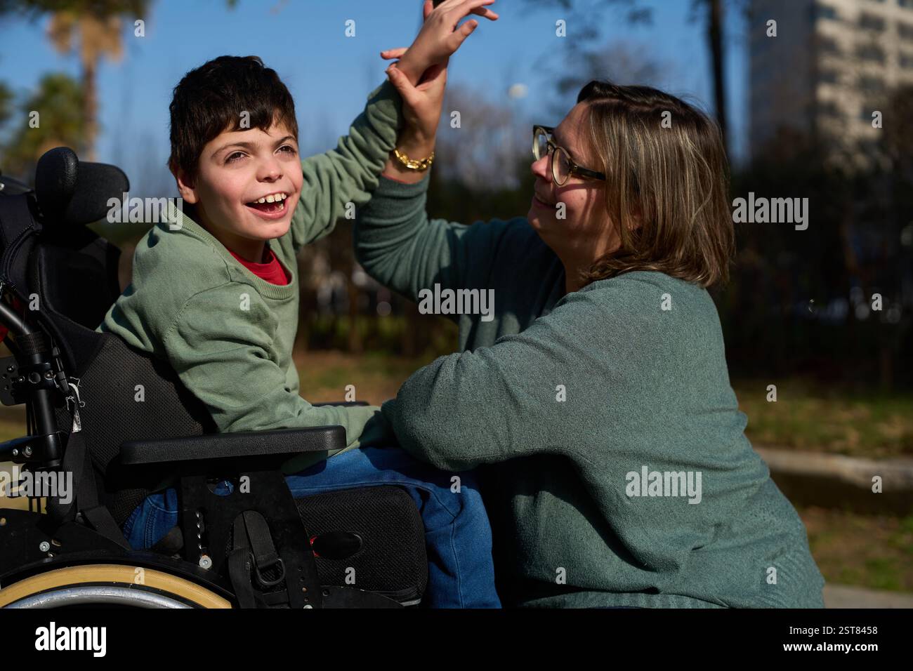 Happy child with disabilities giving high five to his educator in a ...