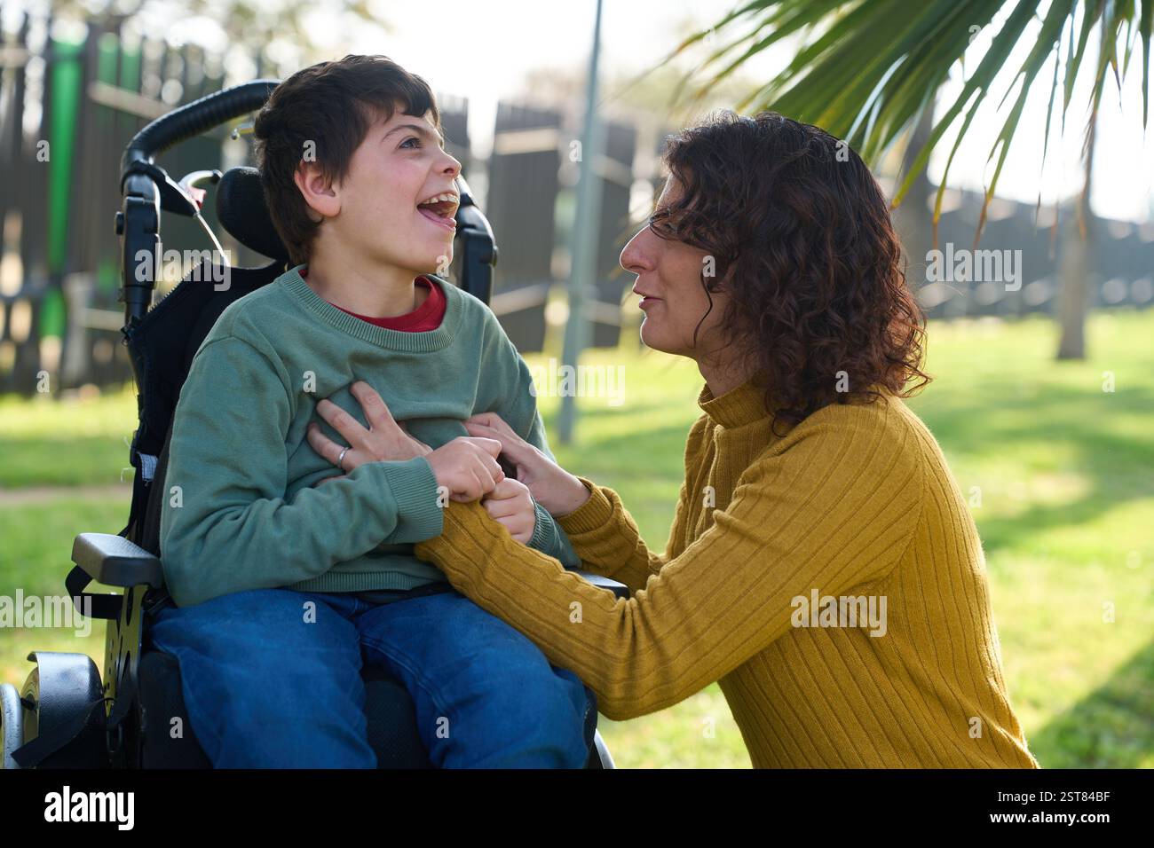 Happy child with disability smiling with his mother at the park ...