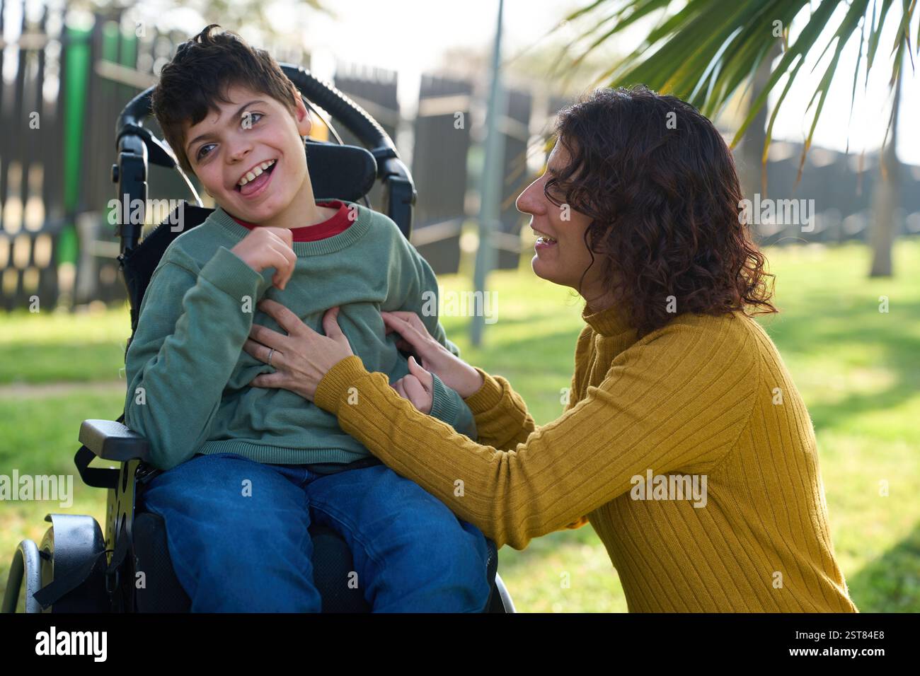 Happy child with disability smiling with his mother in a wheelchair in ...