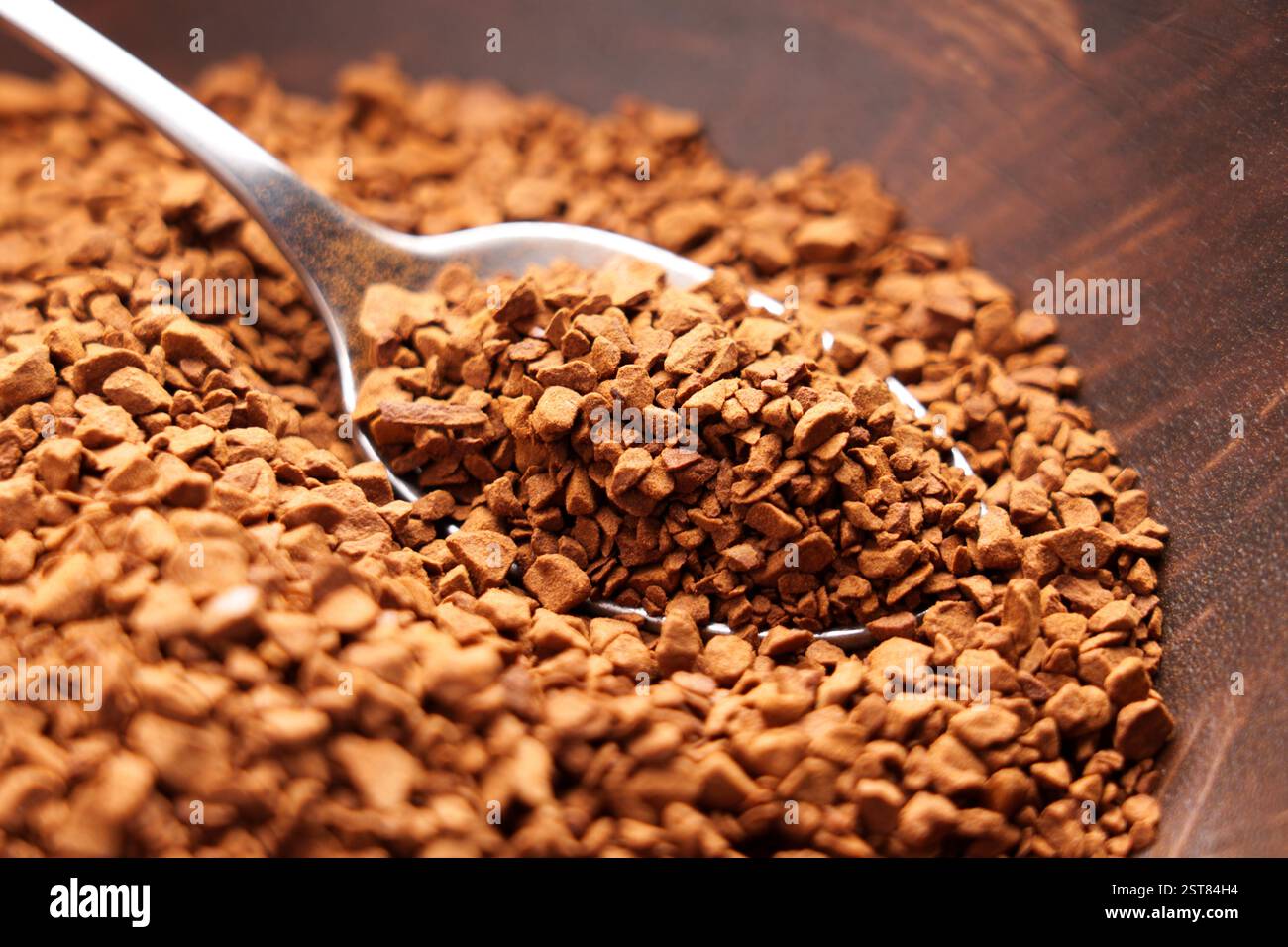 Particles of granulated instant coffee in rustic wood bowl with metal ...