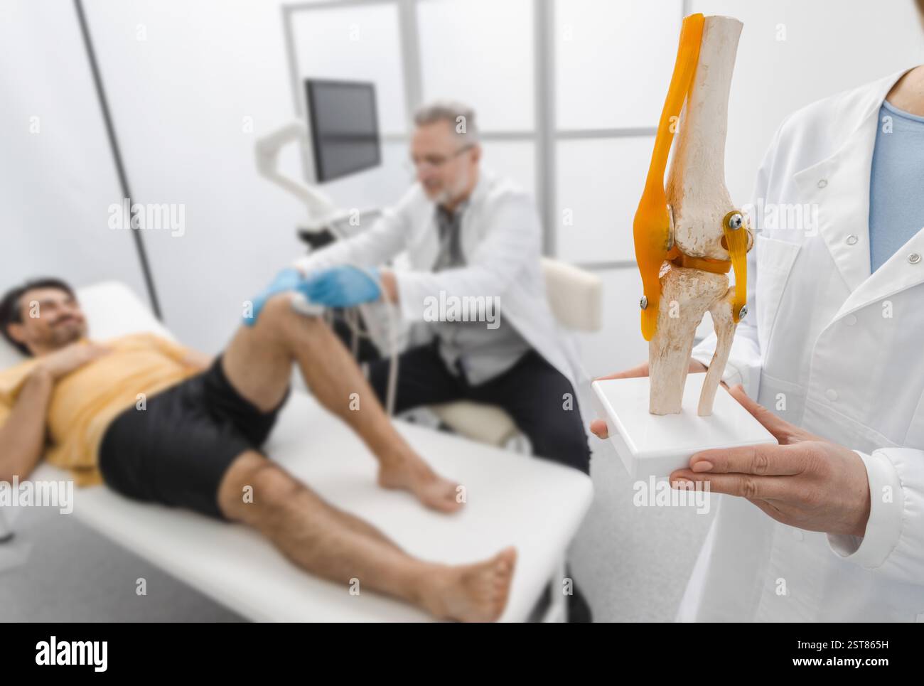 Orthopedic holds knee model during consultation and scanning of injured ...