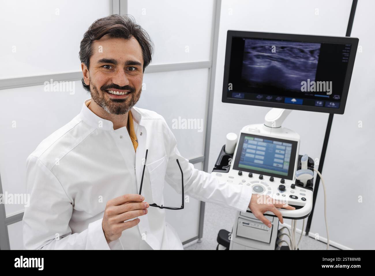 Positive sonographer at his workplace in medical clinic conducts ...