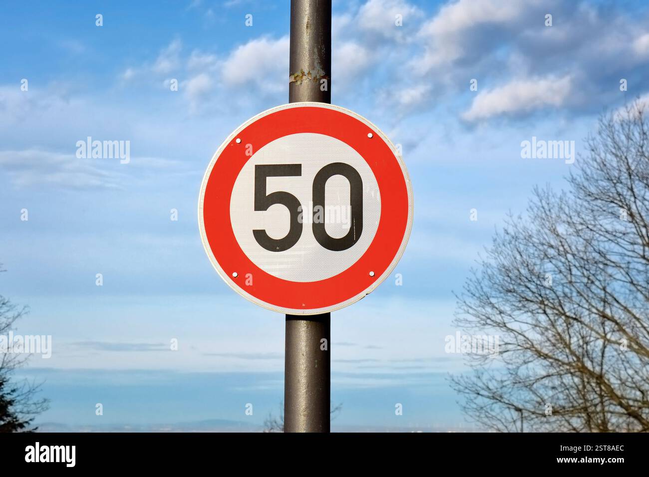 Red round 50km/h speed limit sign on highway in front of blue sky Stock ...