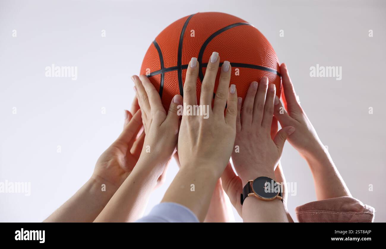 Unity concept. People holding basketball ball together indoors, closeup ...