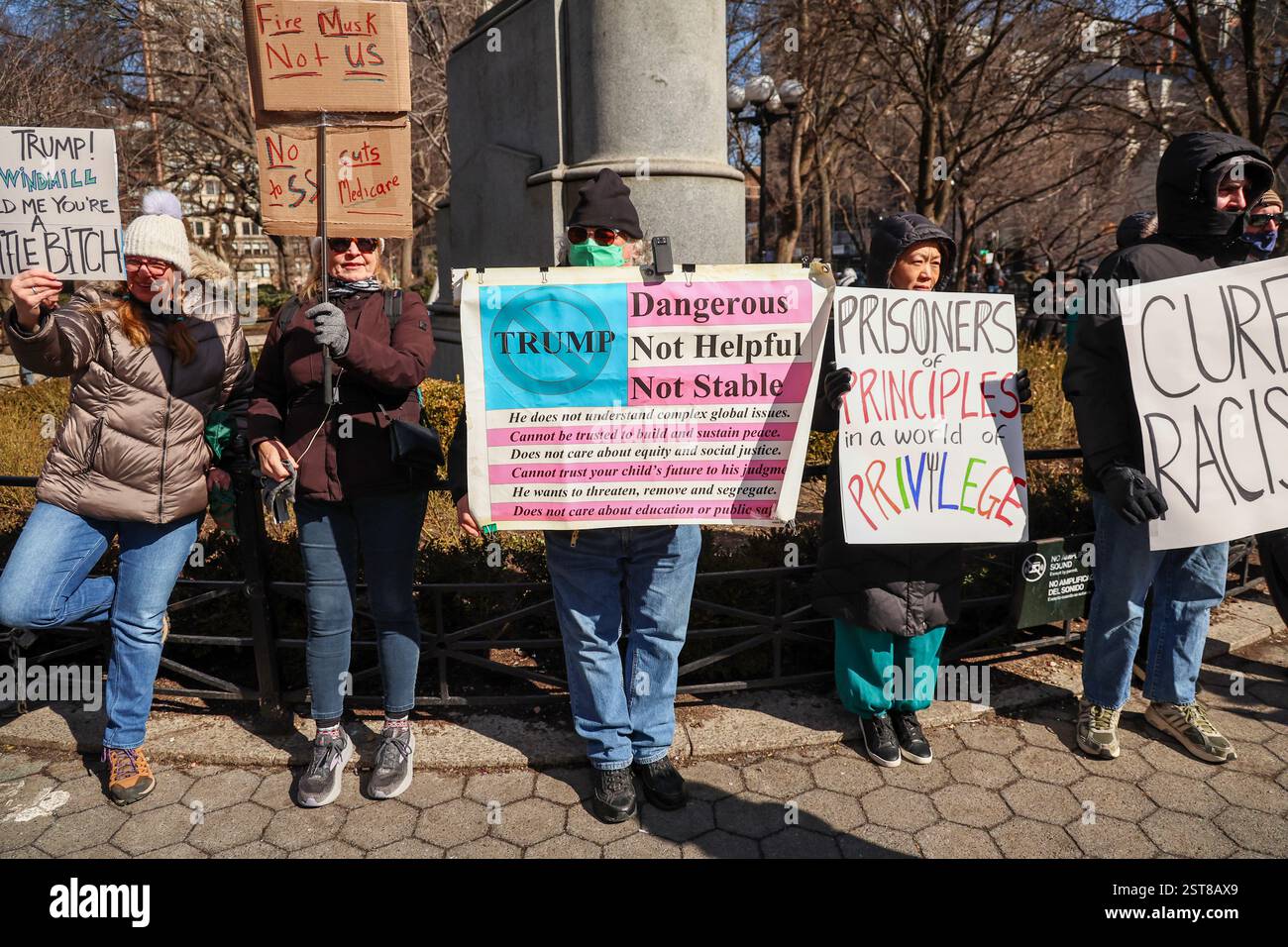 People hold up placards opposed to the policies of President Donald ...