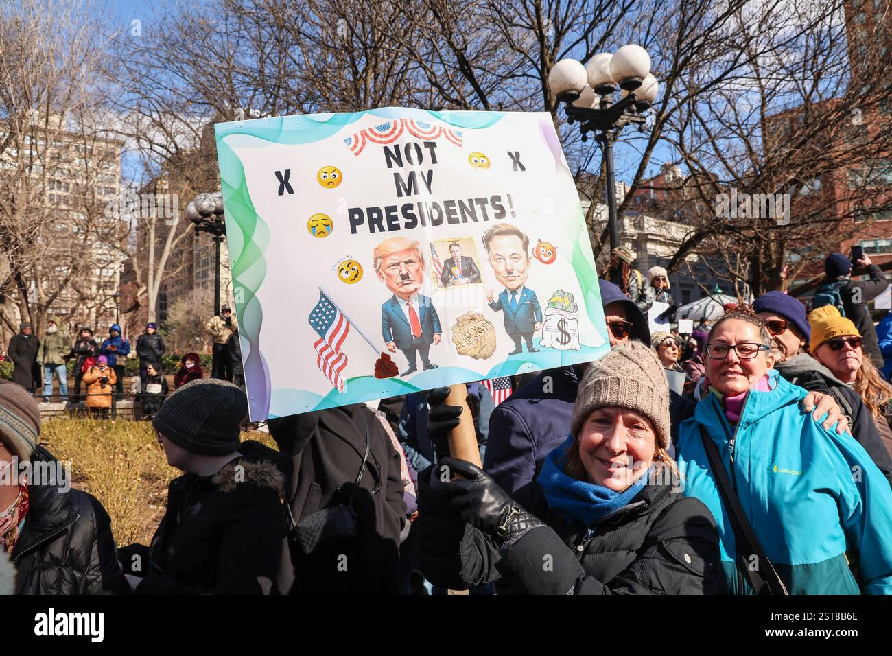 A woman holds up a sign opposed to the policies of President Donald ...