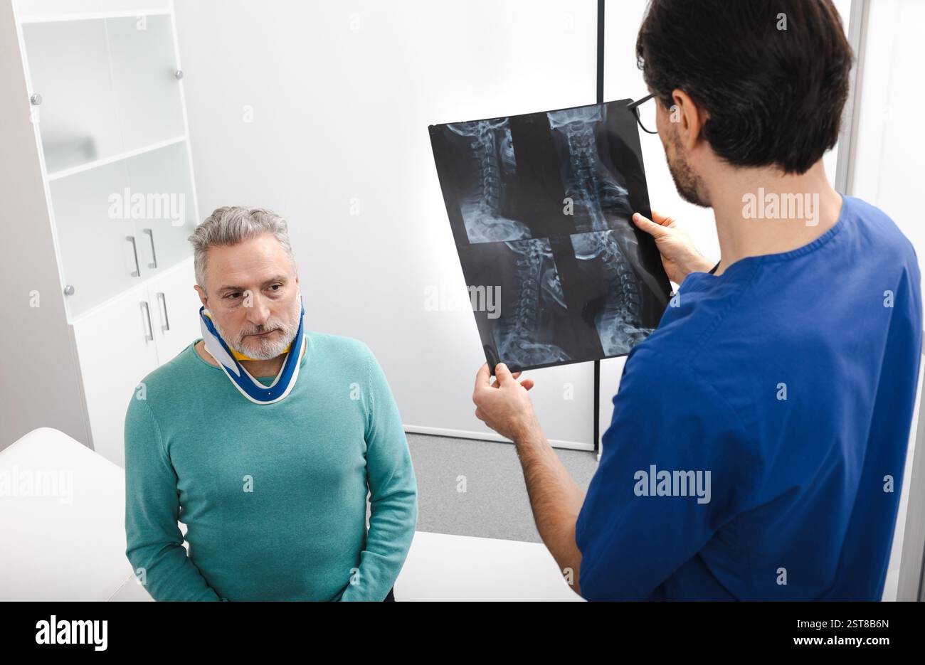 Orthopedist-traumatologist examines MRI images while patient in neck ...