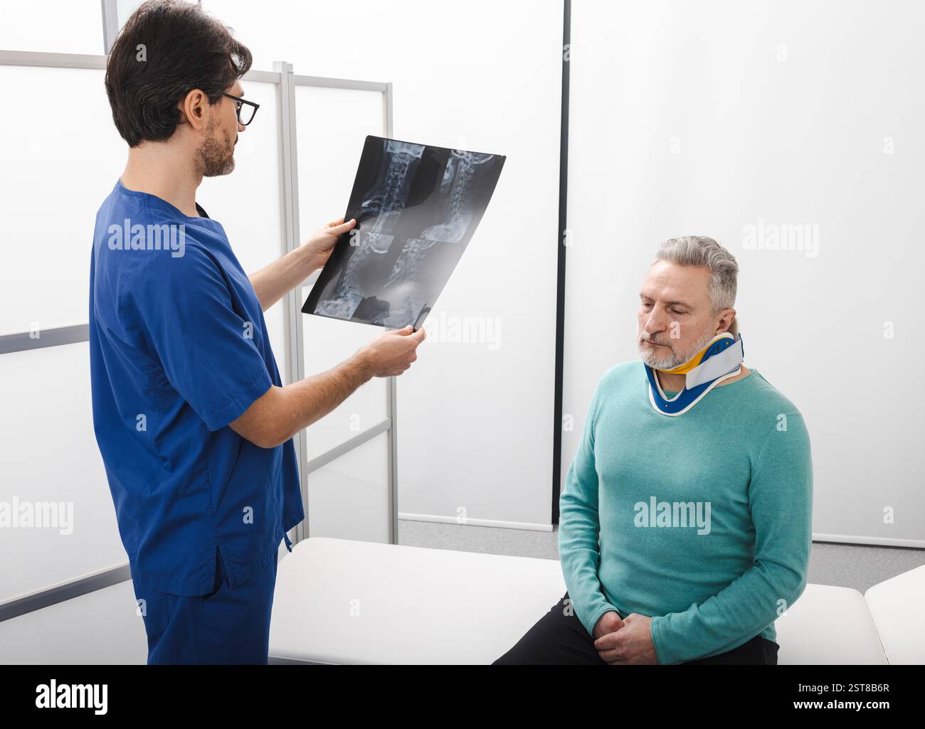 Healthcare worker holds neck X-ray images while discussing them with a ...