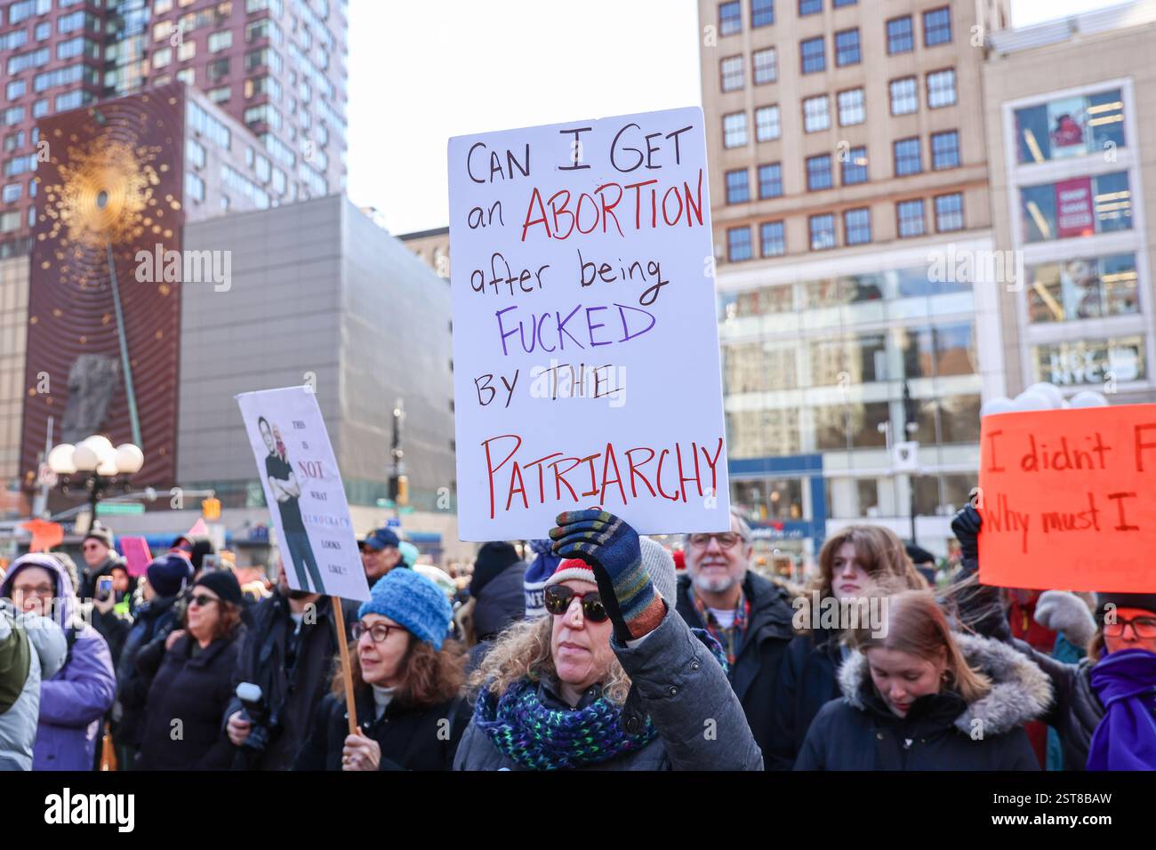 A woman holds up a placard opposed to the policies of President Donald ...