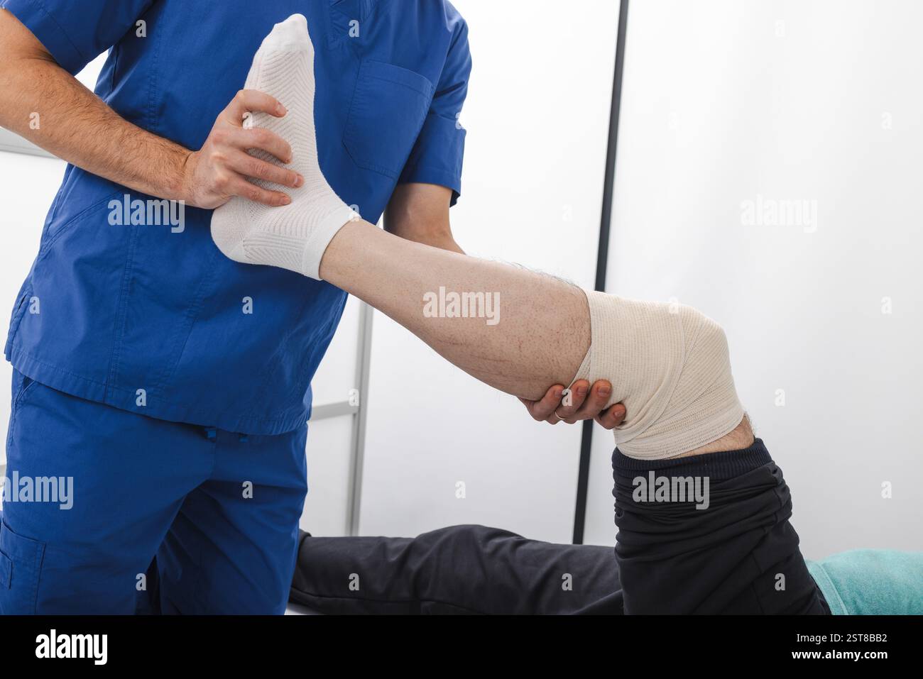 Physical therapist assists patient with leg rehabilitation in a ...