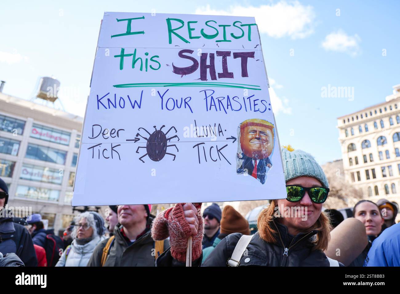 A woman holds up a placard opposed to the policies of President Donald ...