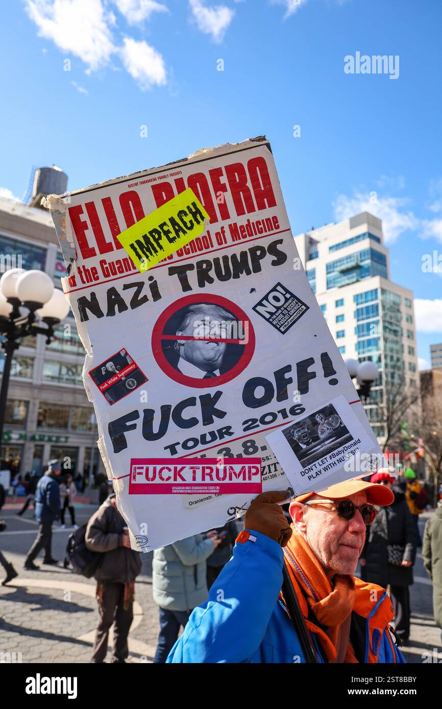 A man holds up a sign opposed to the policies of President Donald Trump ...