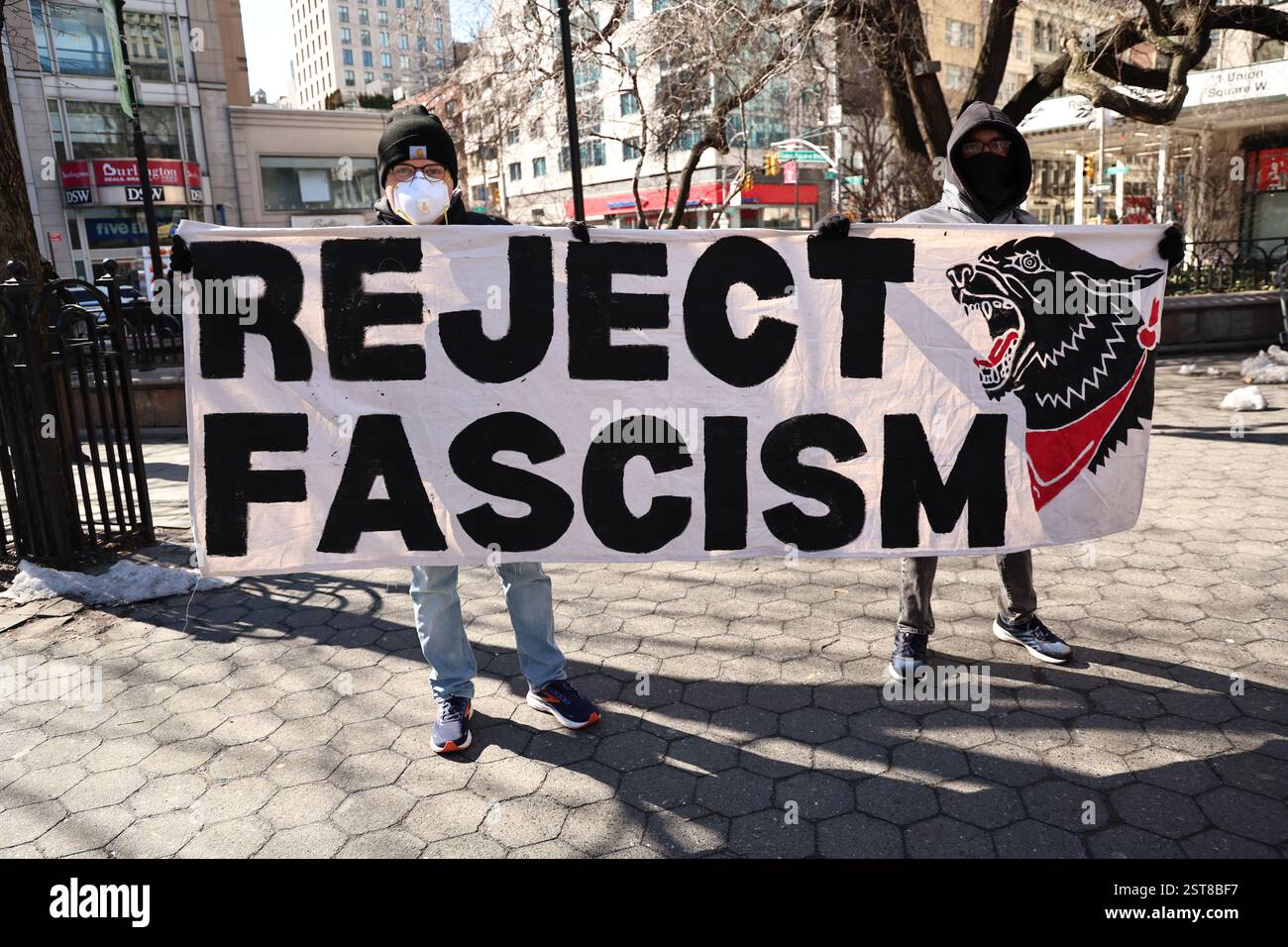 People hold up a banner opposed to the policies of President Donald ...