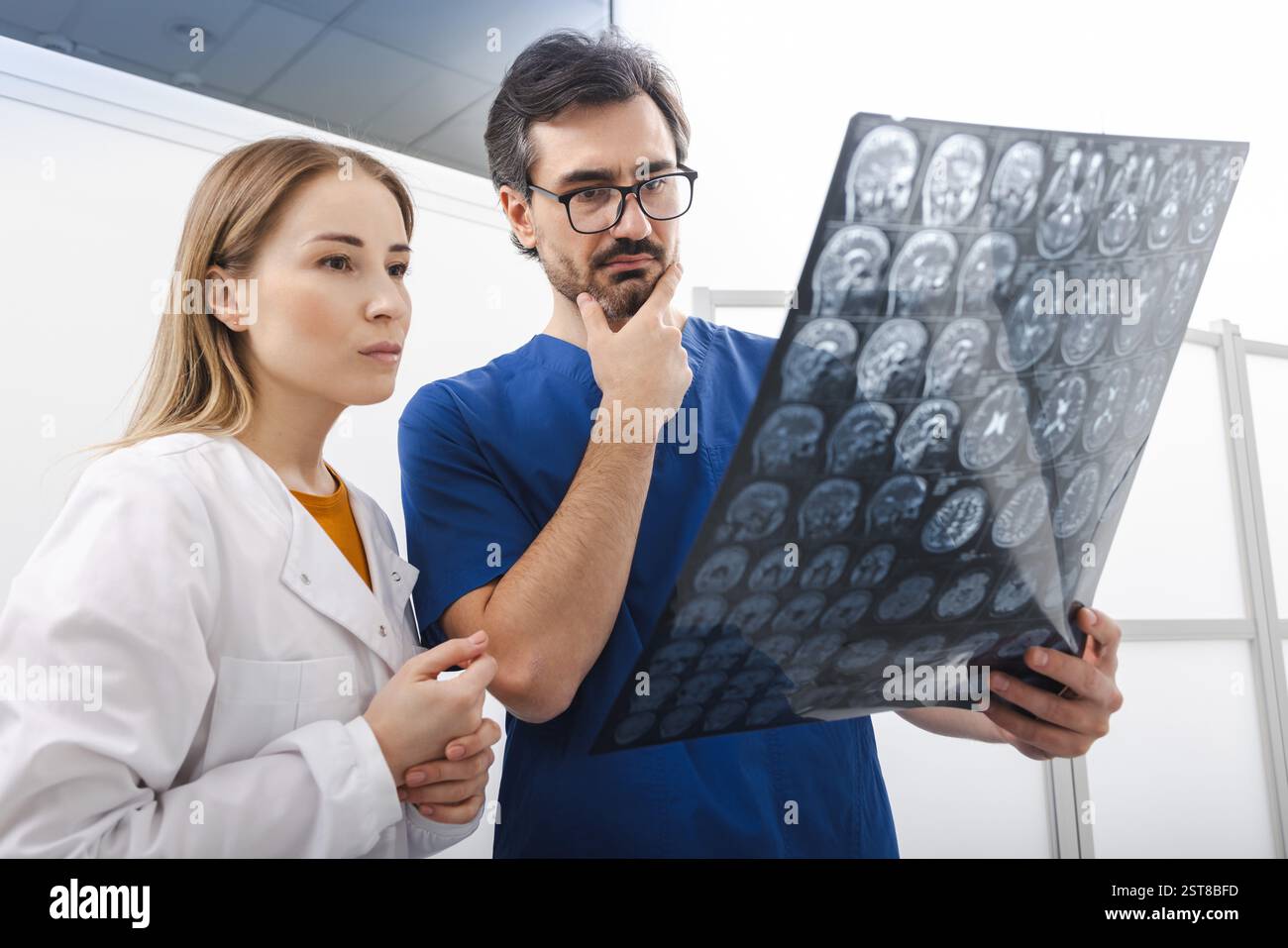 Doctor with MRI of patient head in hands is standing in hospital with ...