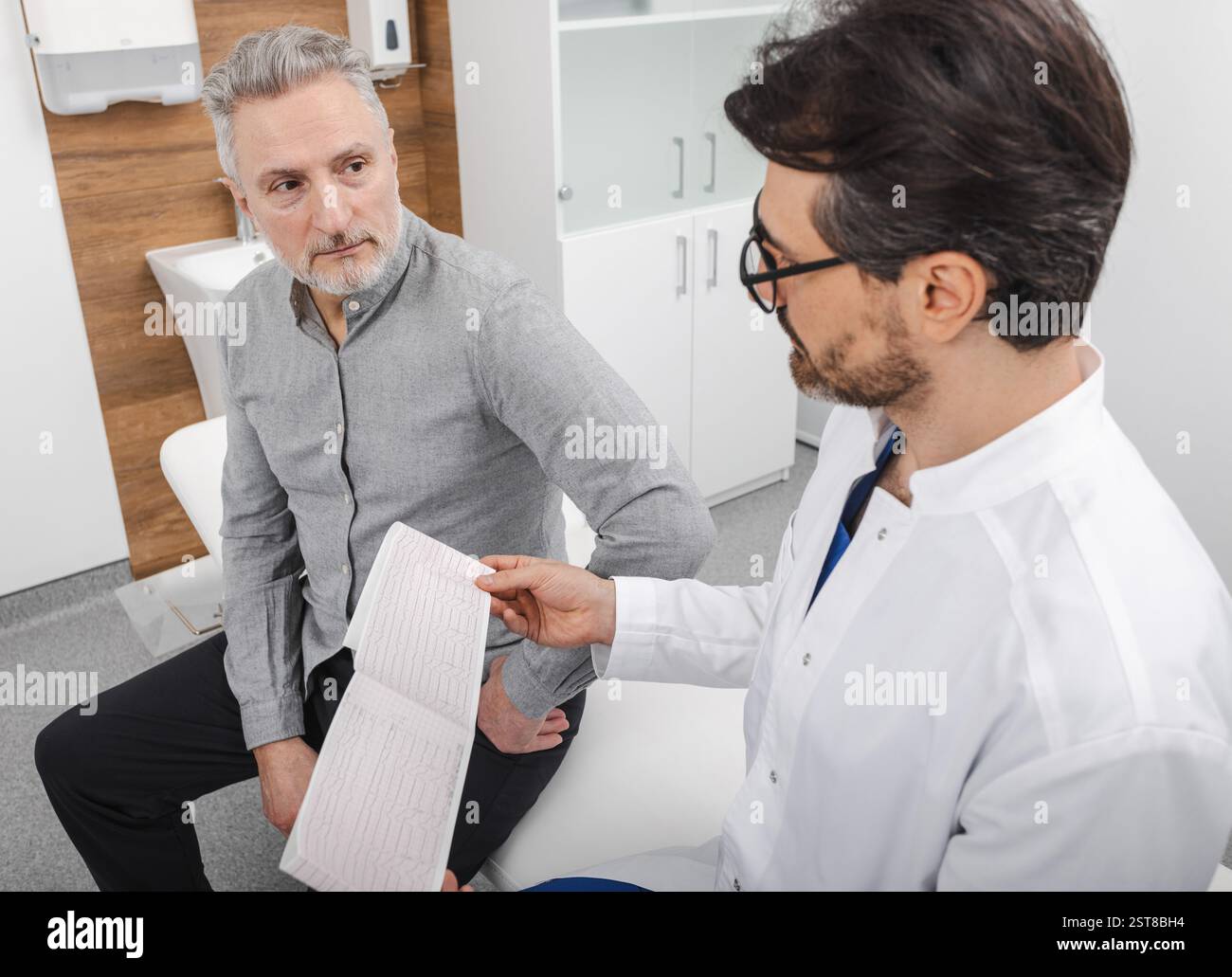 Doctor cardiologist analyzes heart electrocardiogram results of senior ...