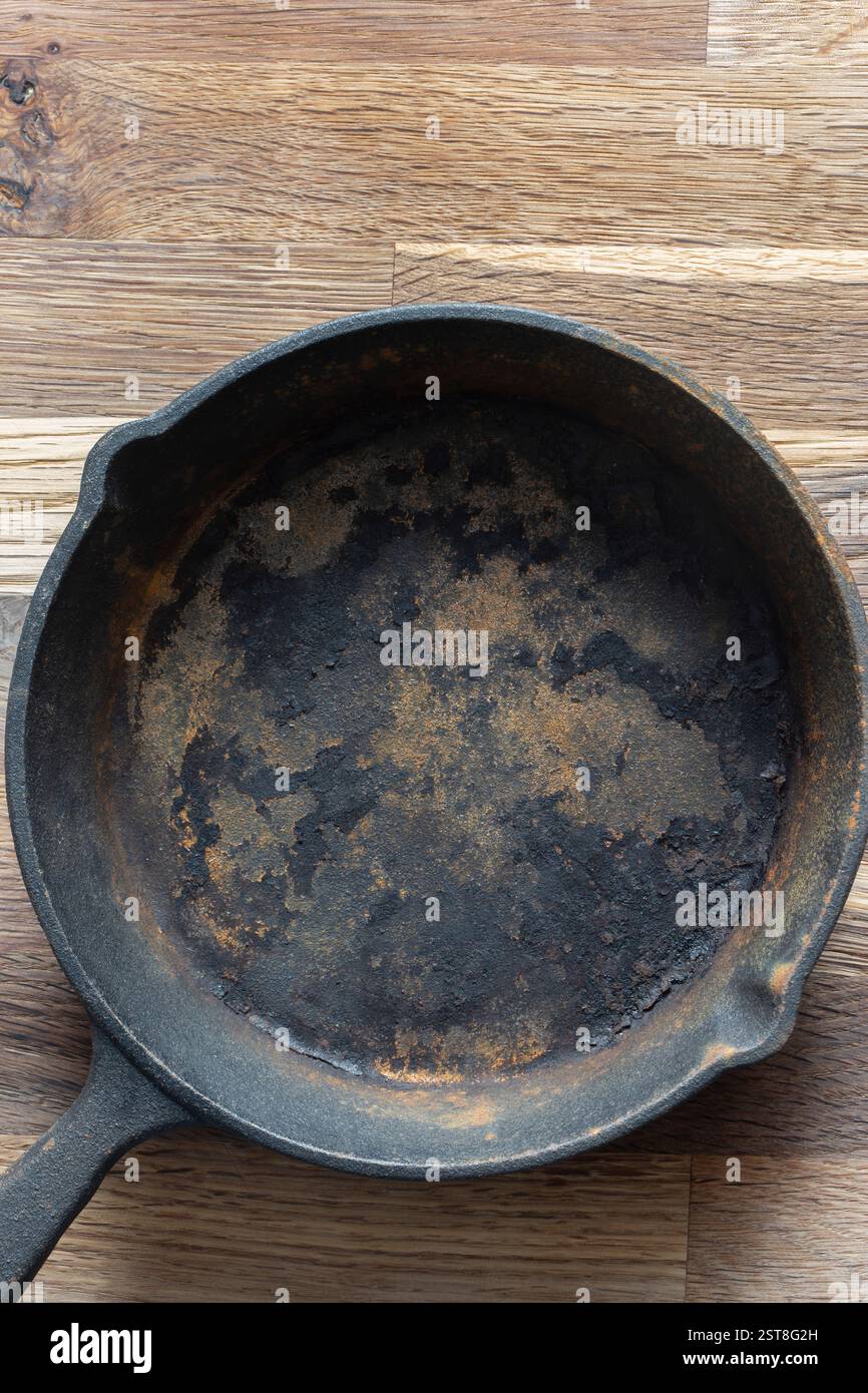 Old rusty cast iron frying pan background. On a wooden chopping cutting ...