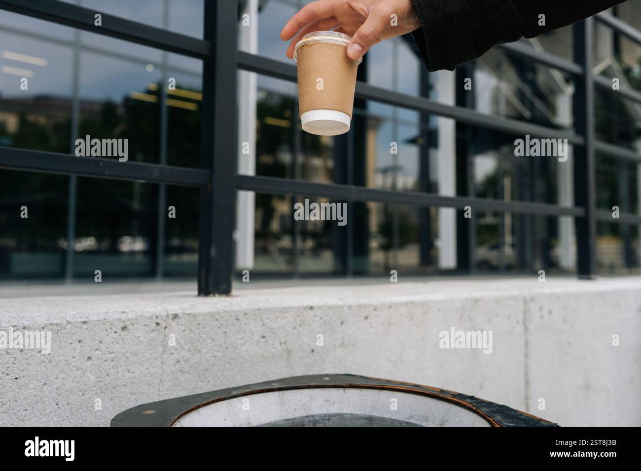 Close-up hands of unrecognizable male throwing disposable coffee cup ...
