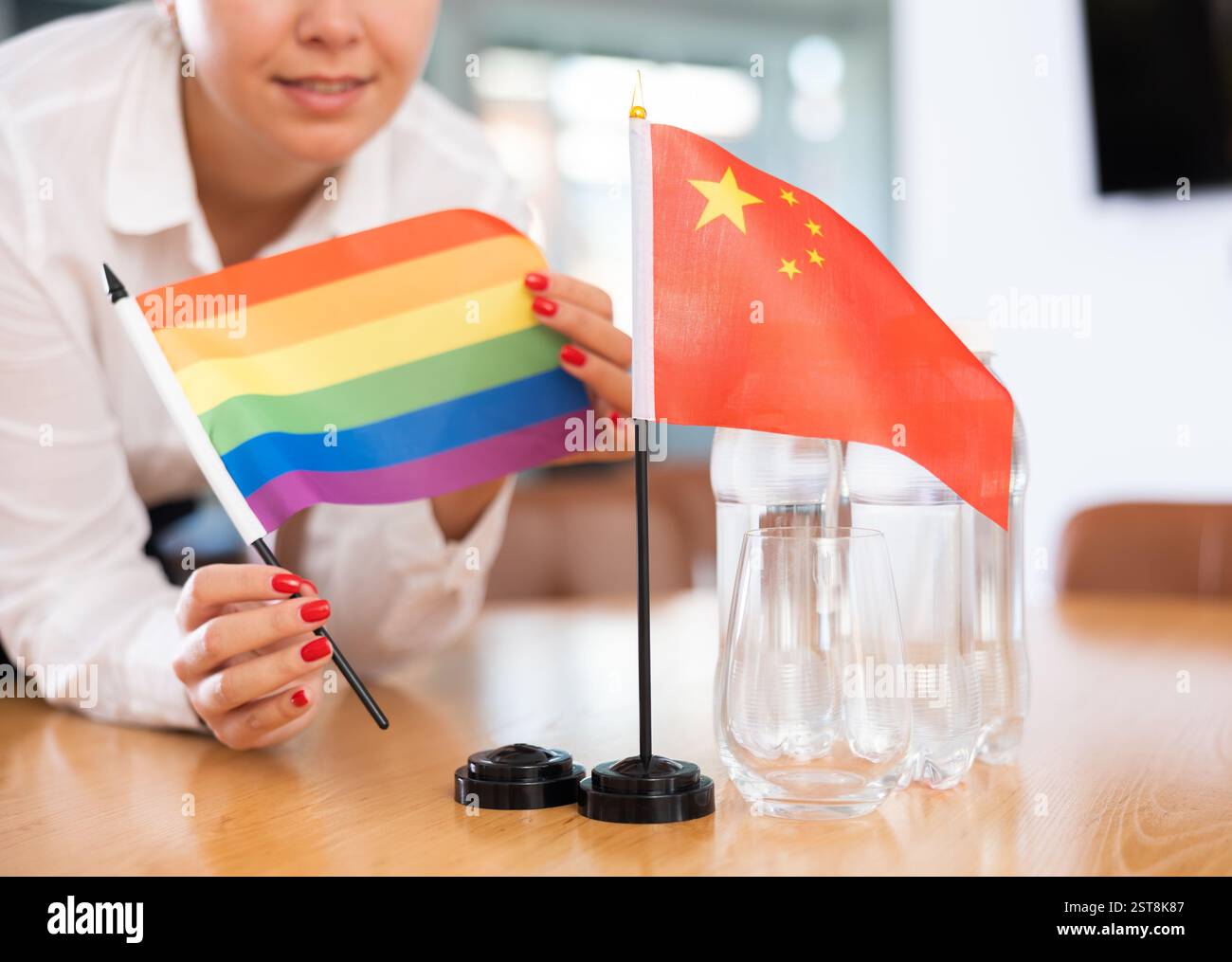 Unrecognizable girl sets midget flags of China and LGBT before ...