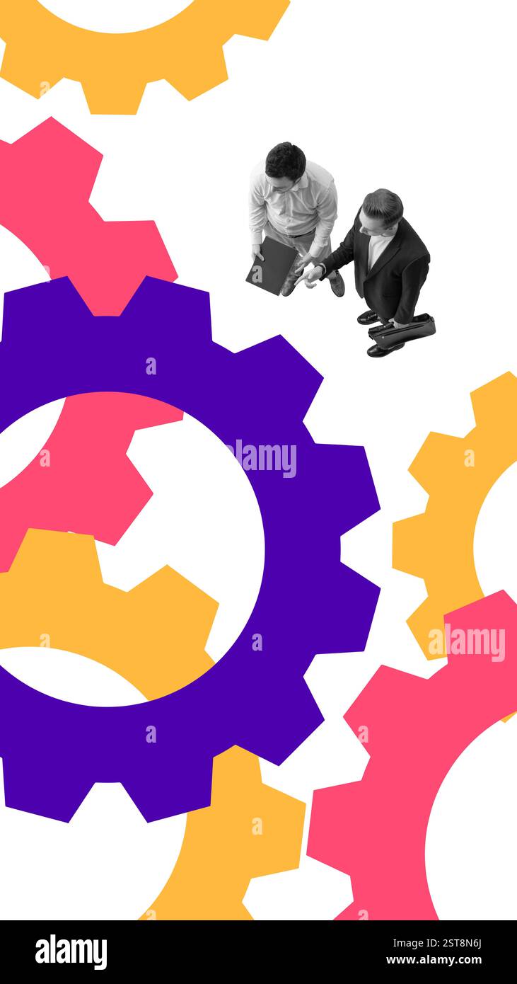 Two businessmen shaking hands while standing near large colorful gears ...
