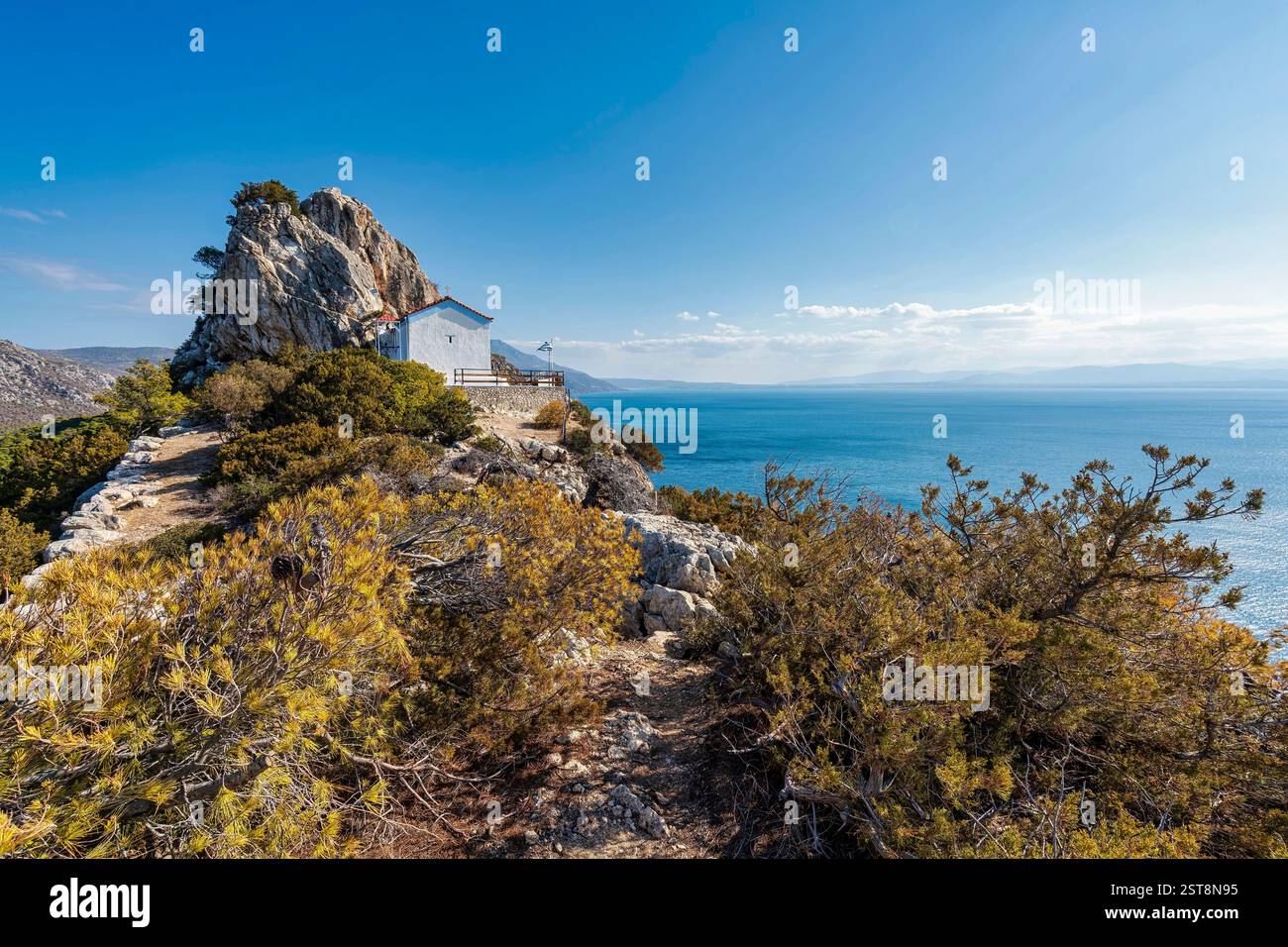A small white chapel sits atop a rocky cliff at Cape Heraion, Greece ...