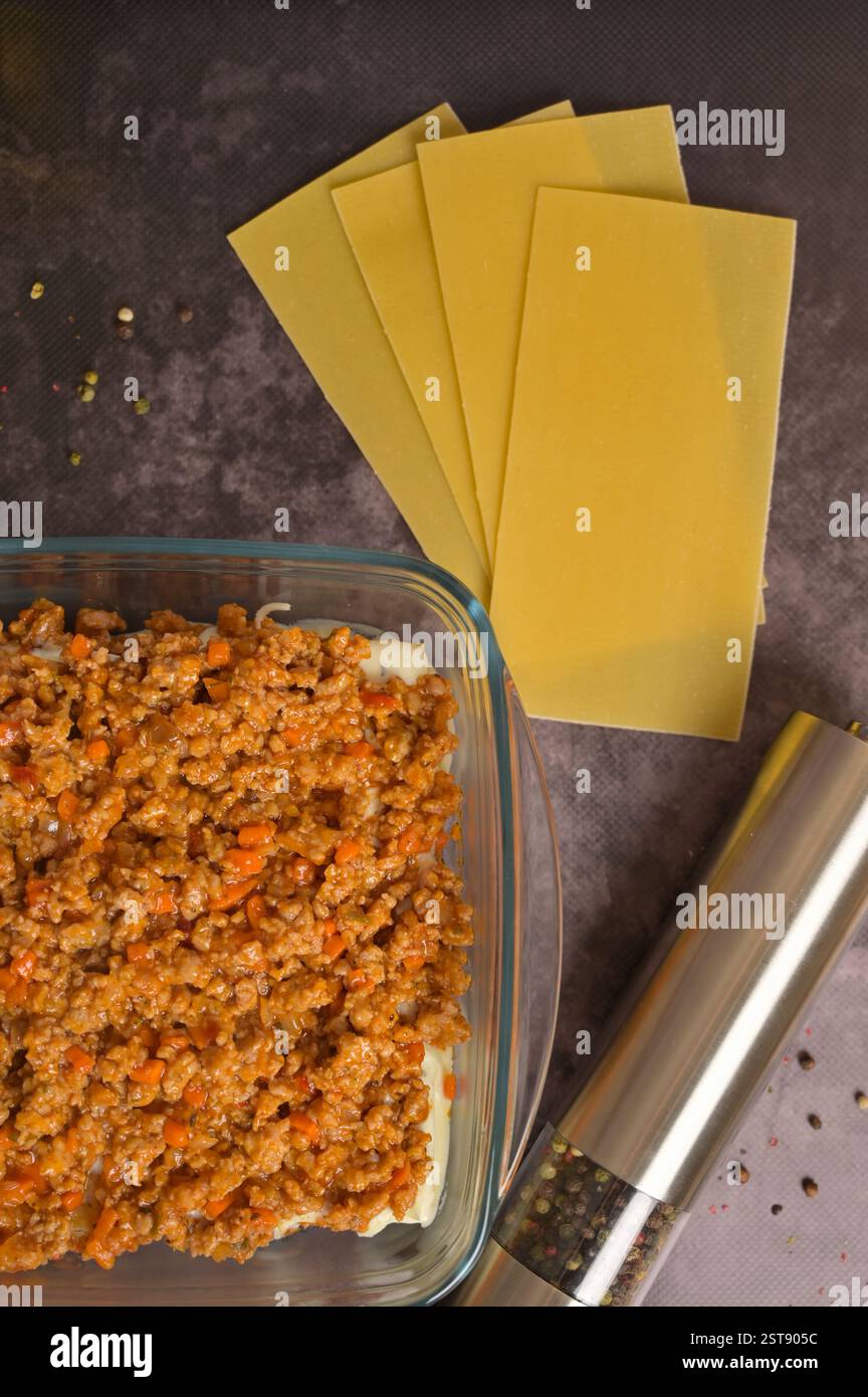 Top view. Bolognese sauce in a glass form. Lasagne pasta sheets, pepper ...