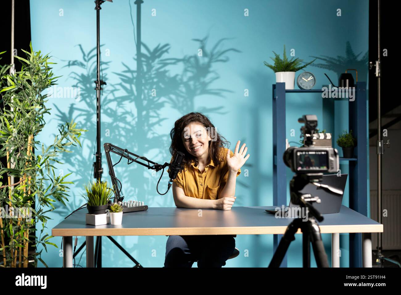 Jolly woman greeting fans, filming vlog with high tech gear in professional studio, speaking ...