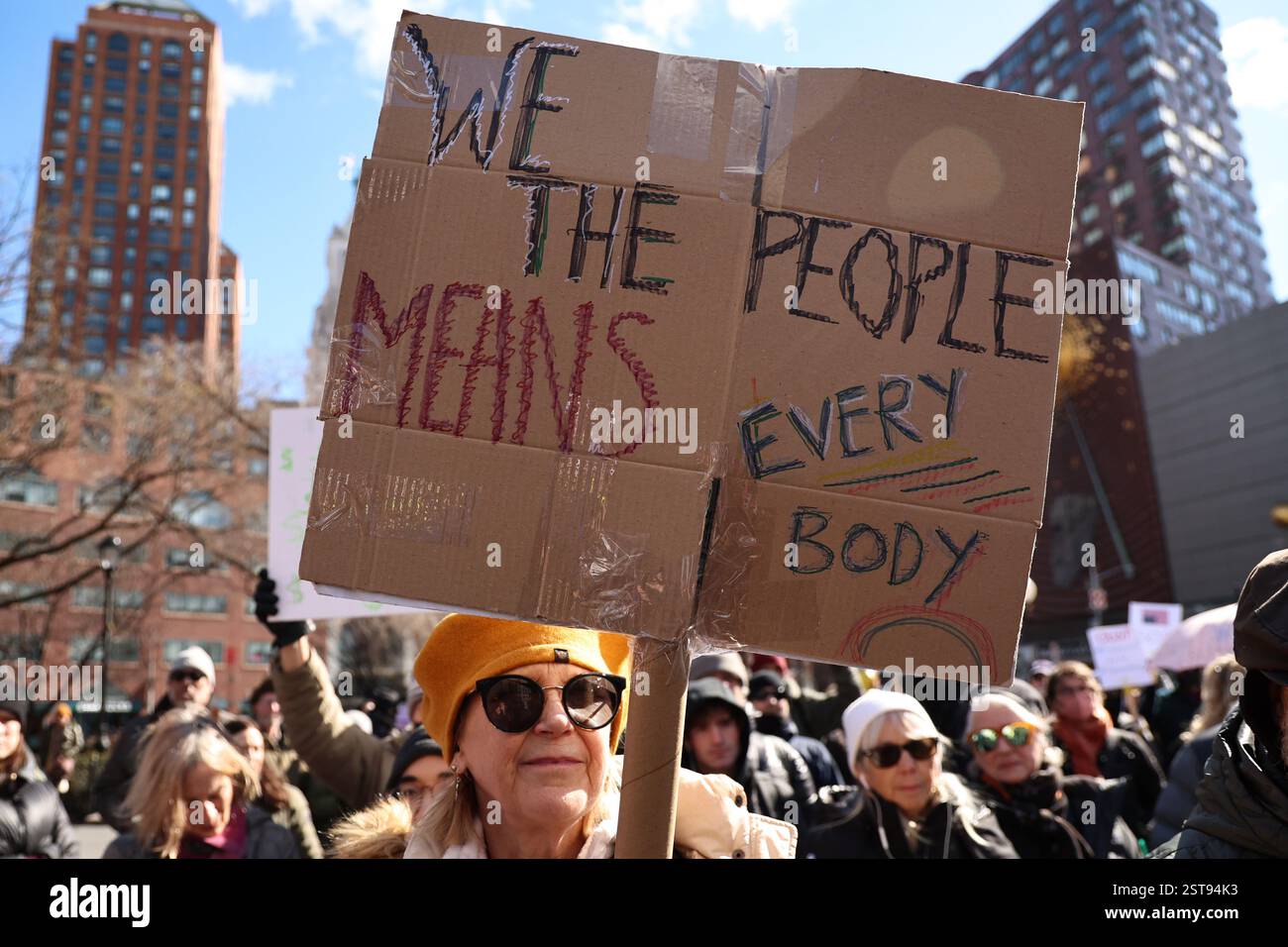 A woman holds up a placard opposed to the policies of President Donald ...