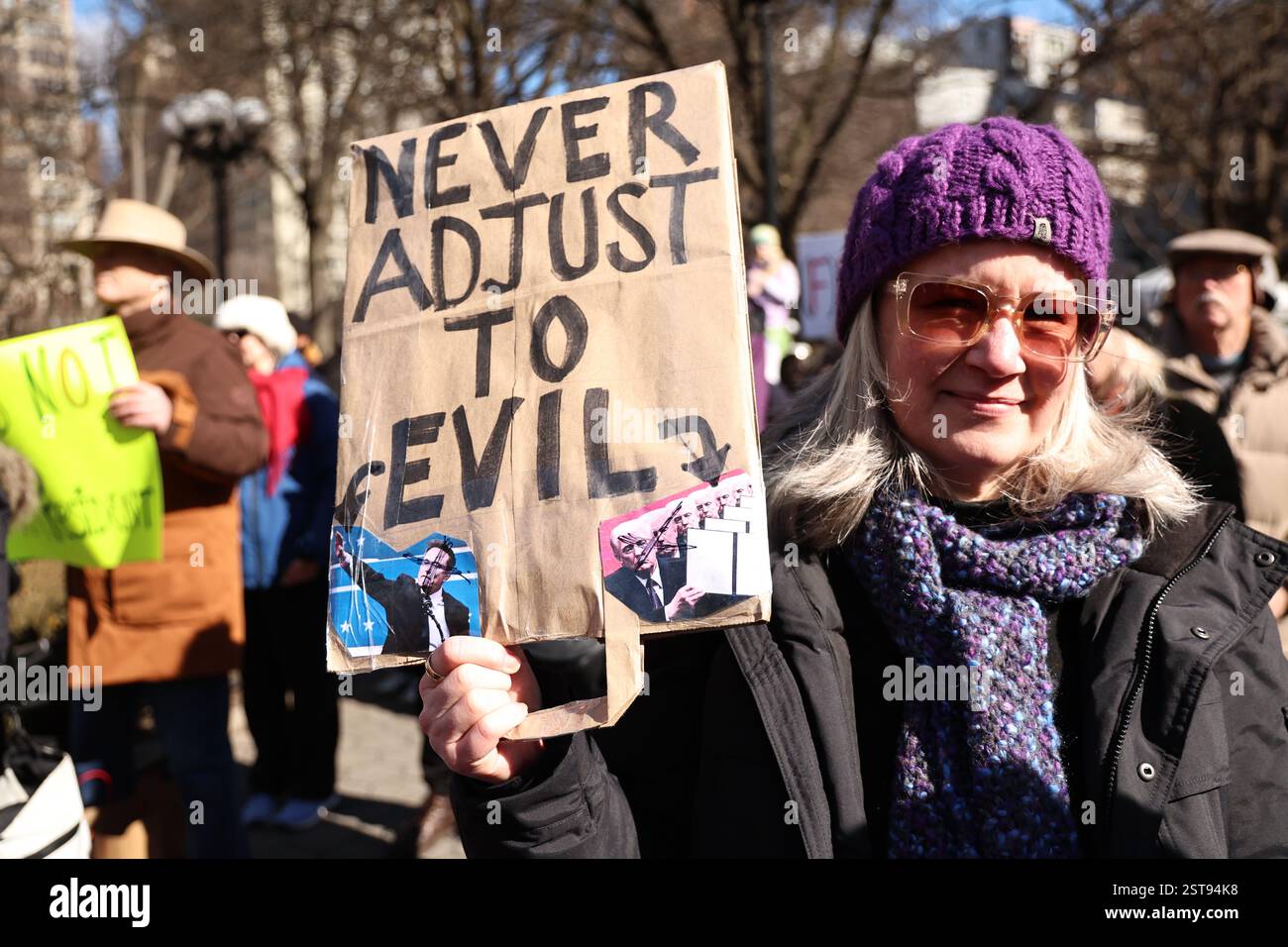 A woman holds up a placard opposed to the policies of President Donald ...