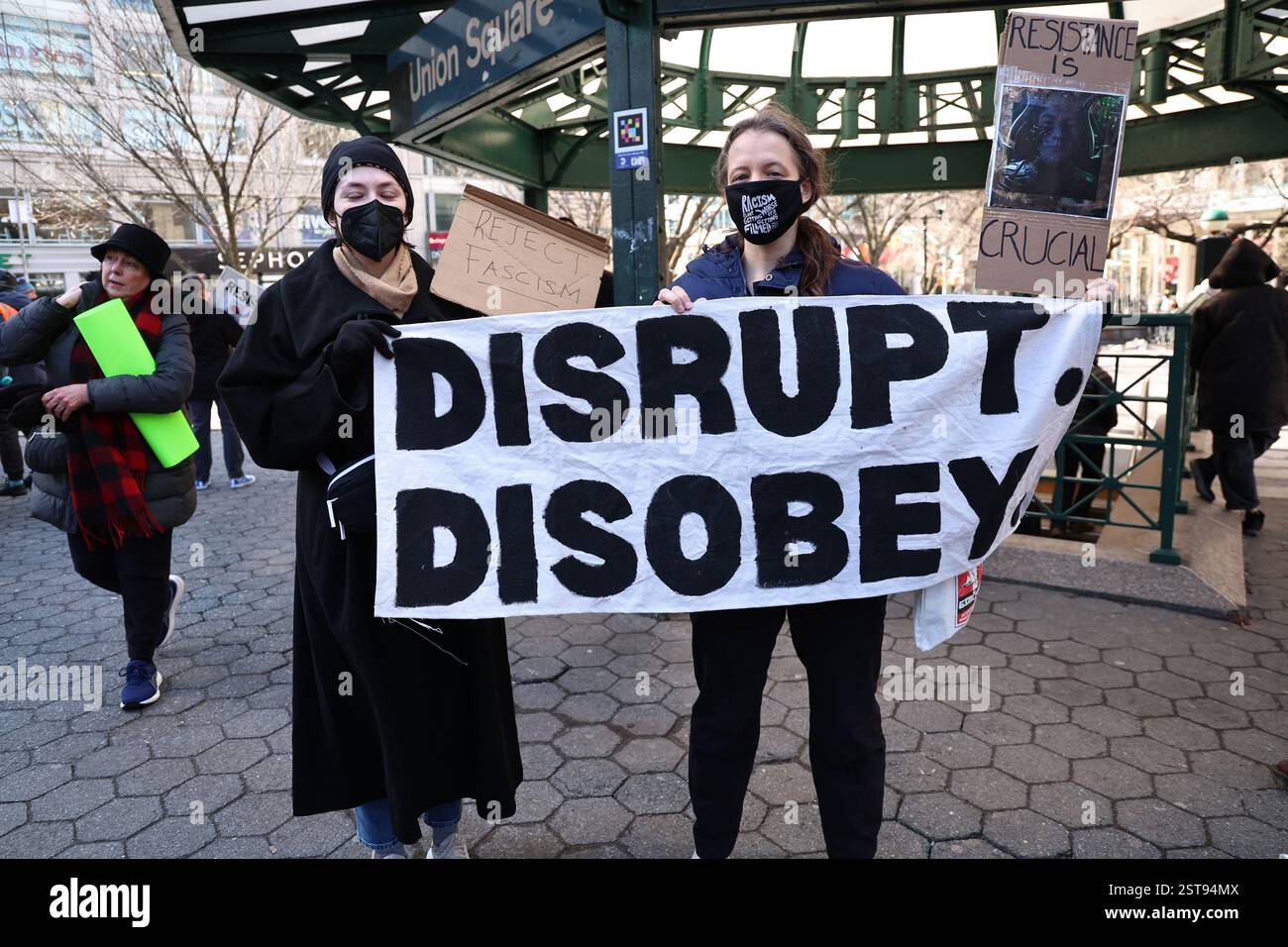 People hold up a banner opposed to the policies of President Donald ...