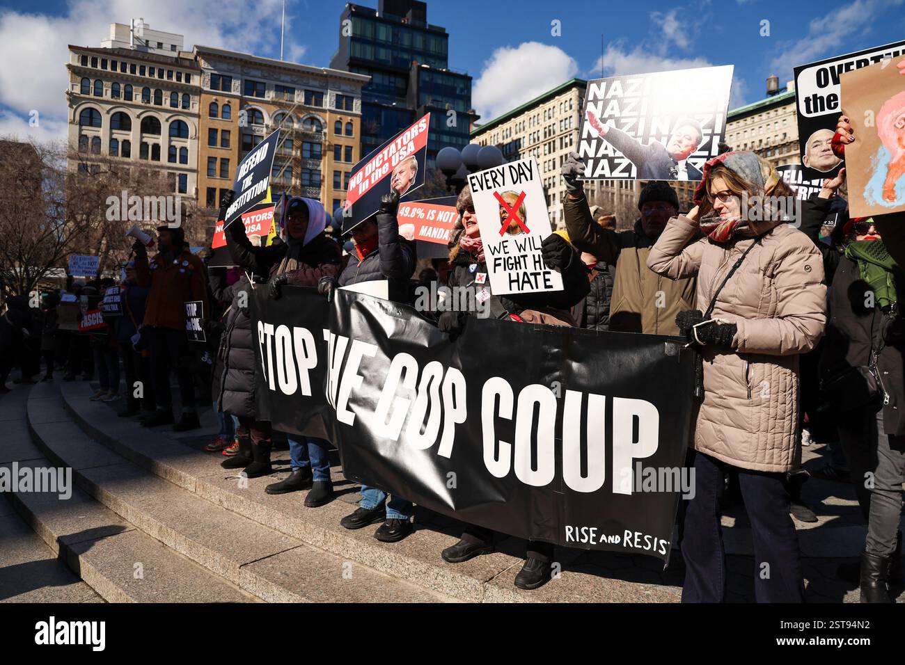 People hold up a banner opposed to the policies of President Donald ...