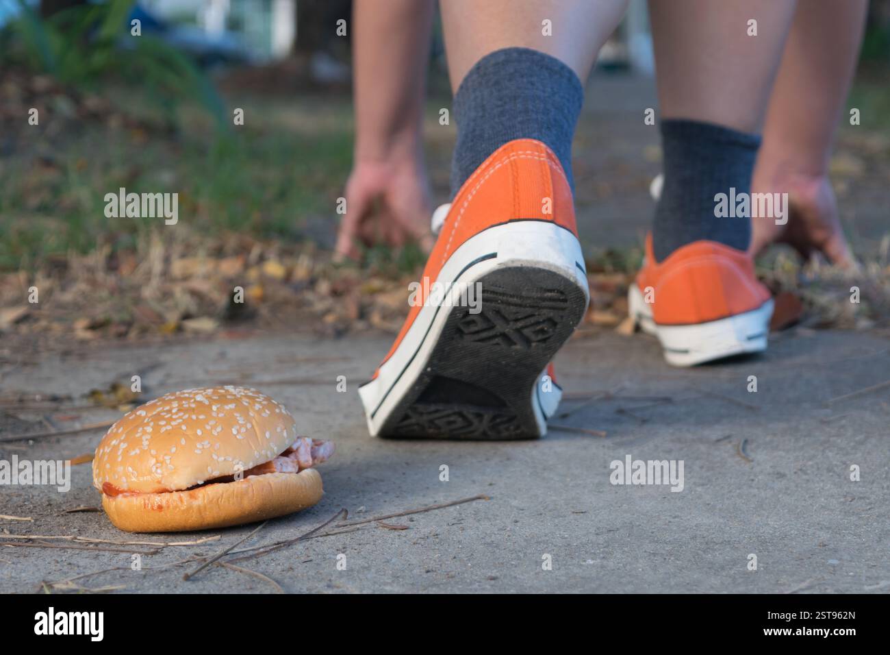 Good bye junk food hamburger left to jogging exercise Stock Photo - Alamy