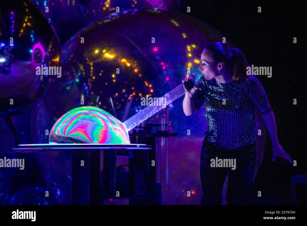 A young Asian American woman blows a multicolored bubble at a Christmas ...