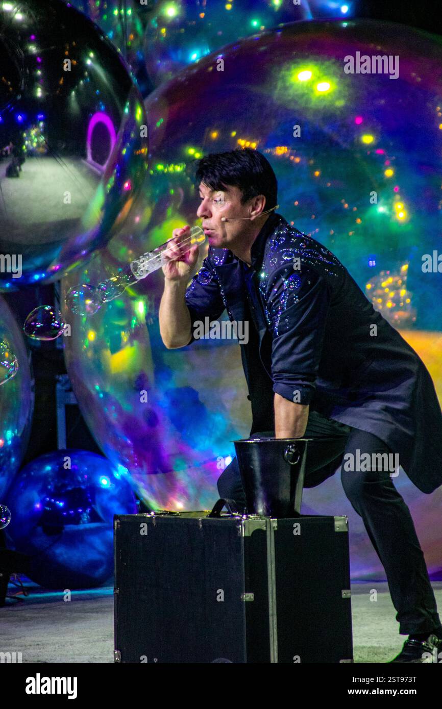 Using a bubble pipe, a young Asian American man creates huge bubbles at ...