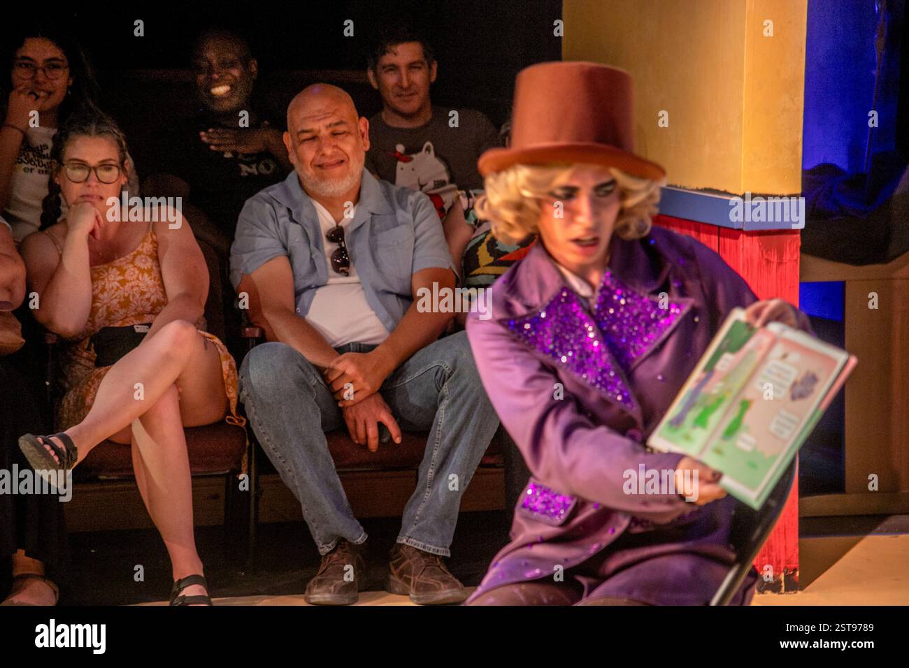 Dolled up in a dress and a wig, a gay female impersonator reads as an ...