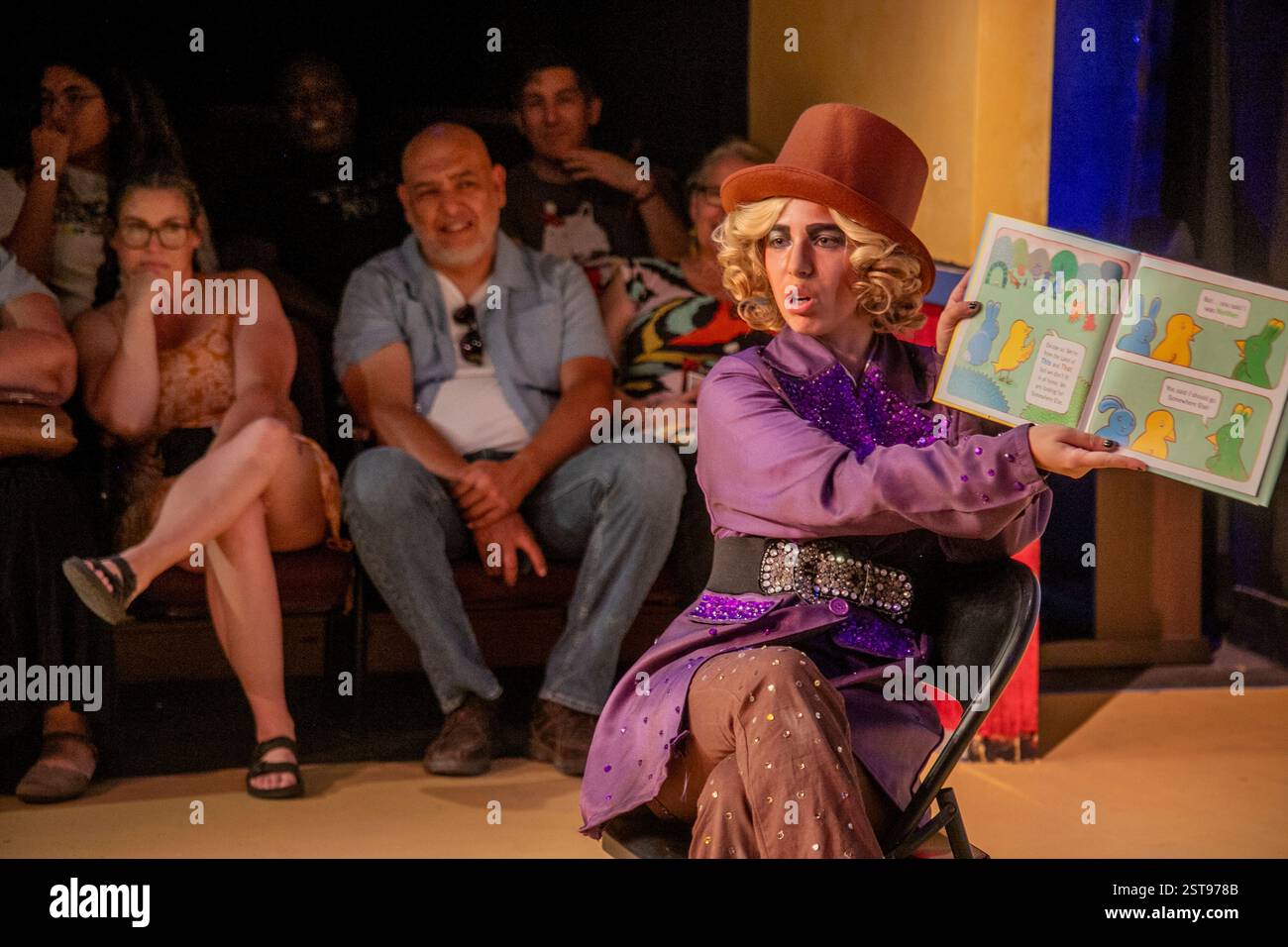 Dolled up in a dress and a wig, a gay female impersonator reads as an ...