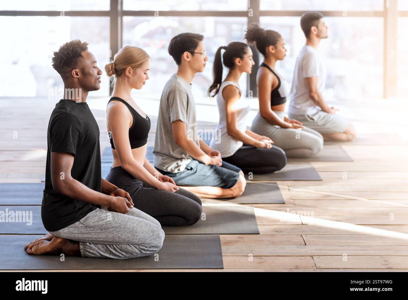 Wellness Concept. Young sporty people in yoga class making meditation ...