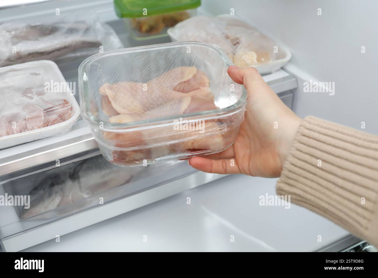 Woman taking frozen chicken drumsticks out of fridge, closeup Stock ...