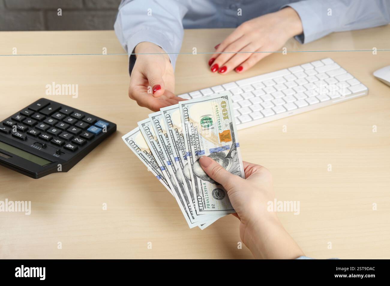 Client giving dollar banknotes to cashier at table in money exchange ...