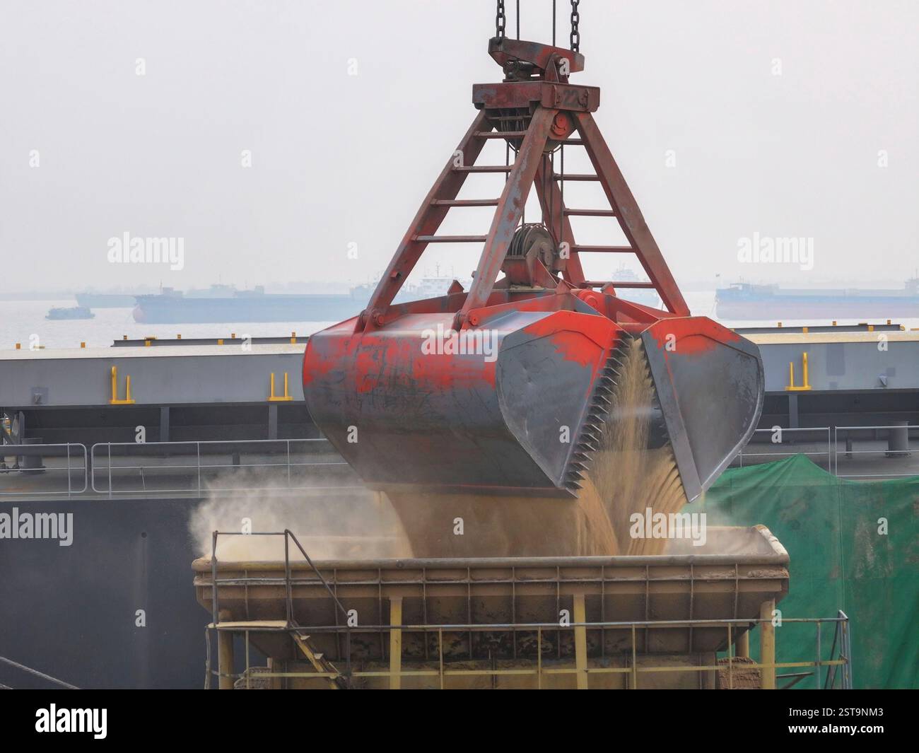 A grab loads barley imported from Australia off a cargo ship at a ...